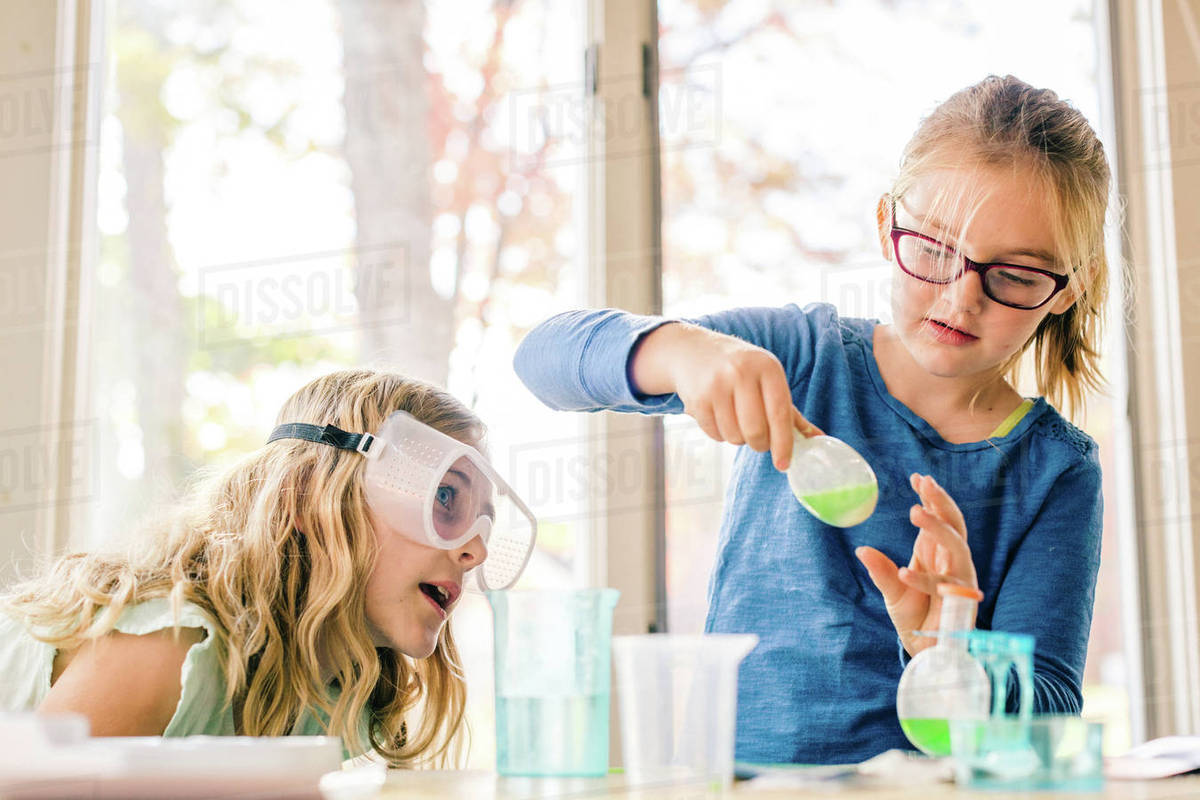 Two girls doing science experiment, shaking liquid in flask - Royalty ...