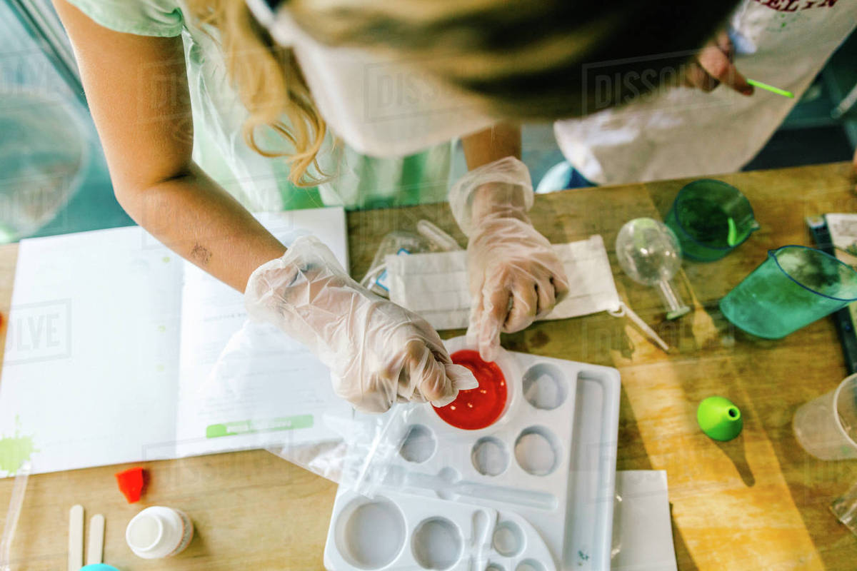 Overhead view of girls doing science experiment, with red liquid ...