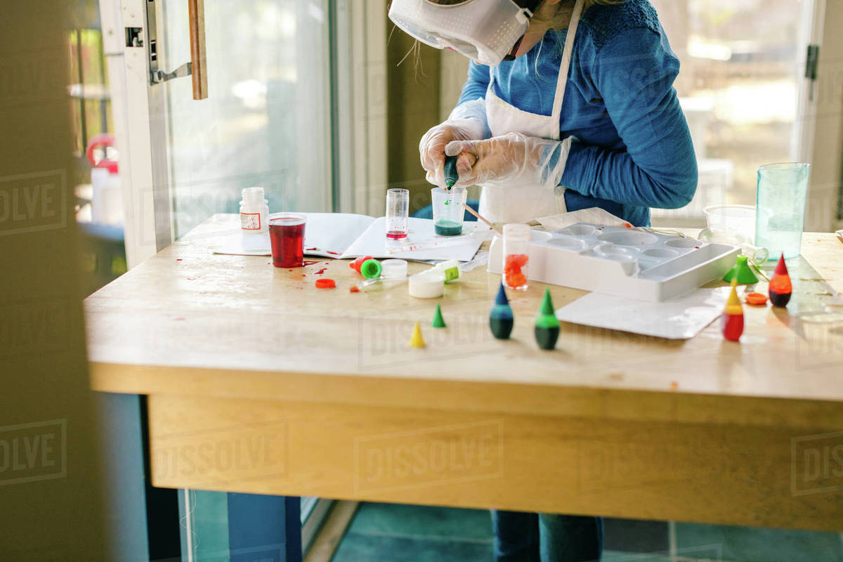Girl doing science experiment, squeezing liquid into measuring cup ...