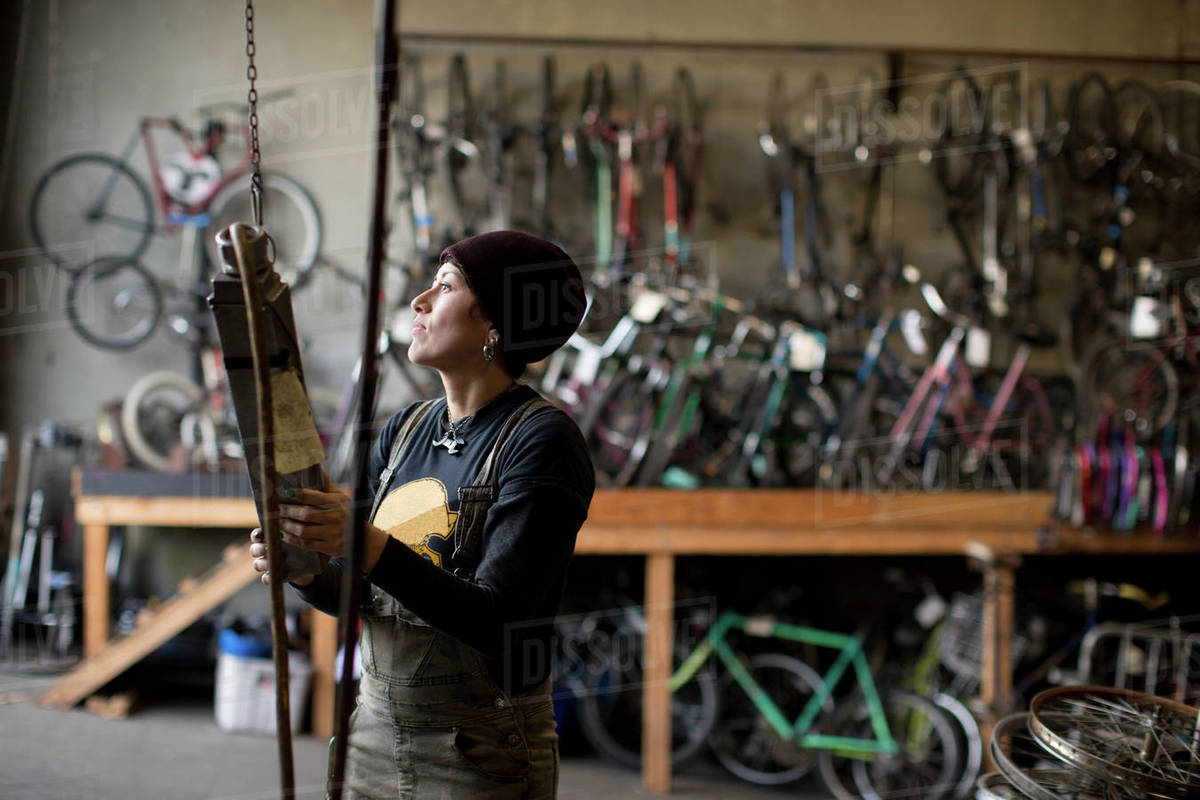 Female metalsmith attaching metal to chain hoist in workshop - Royalty ...