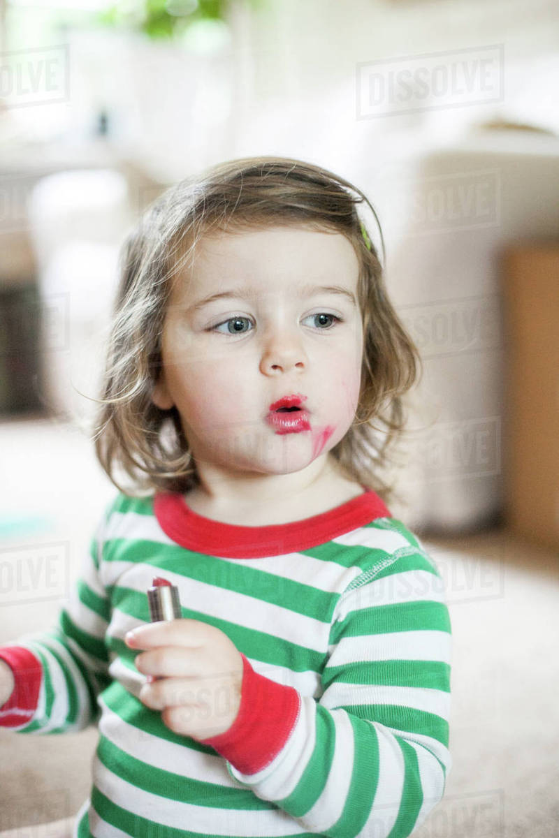 Baby girl playing with lipstick - Stock Photo - Dissolve