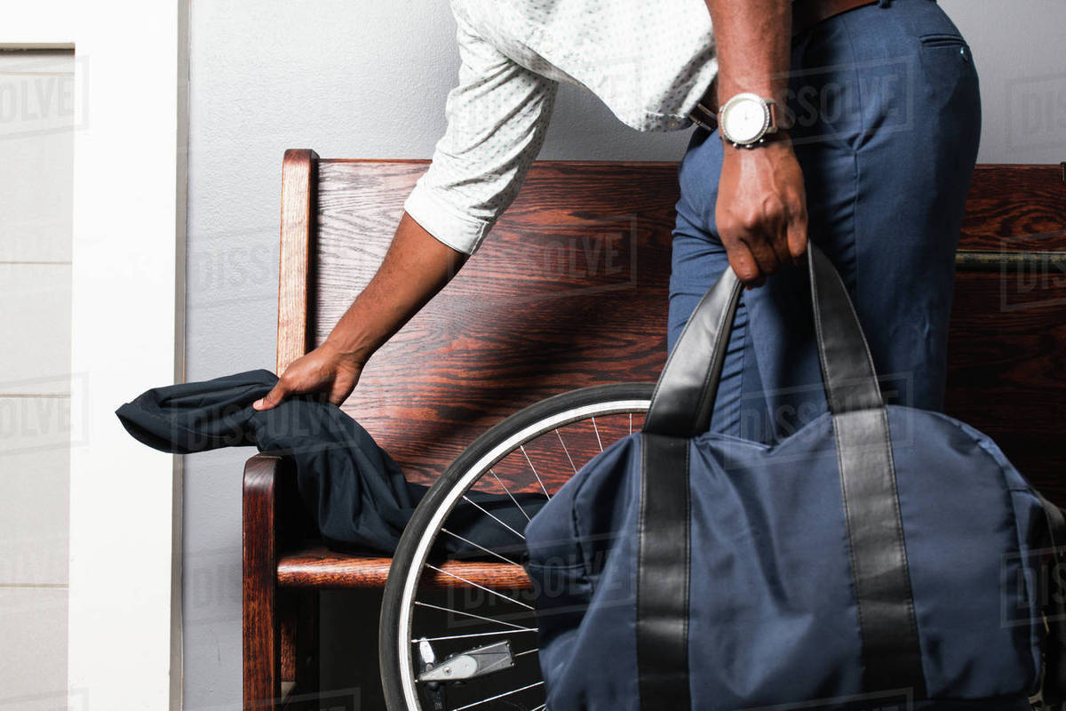 Mid section of young businessman picking up jacket in hallway - Royalty ...