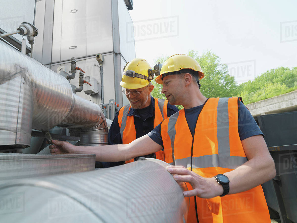 Workers examining machinery on site - Royalty-free Stock Photo | Dissolve