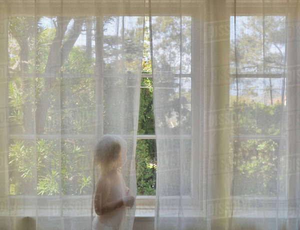 Boy standing behind sheer curtain - Royalty-free Stock Photo | Dissolve