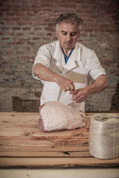 Butcher tying meat in shop - Stock Photo - Dissolve