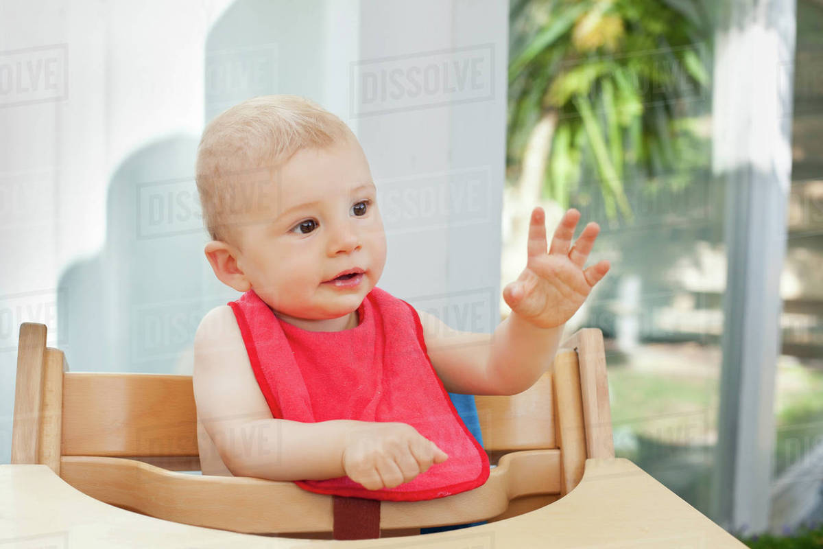 Baby boy wearing bib in high chair - Royalty-free Stock Photo | Dissolve