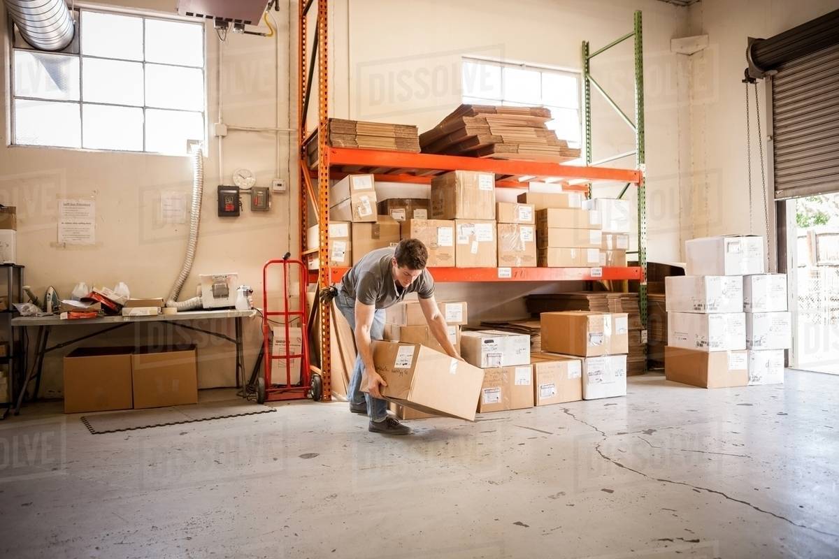 Worker lifting cardboard box - Royalty-free Stock Photo | Dissolve