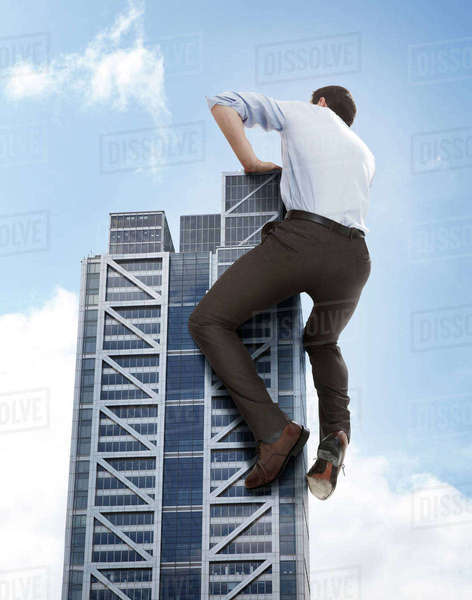 Oversized businessman climbing skyscraper, low angle view - Stock Photo ...