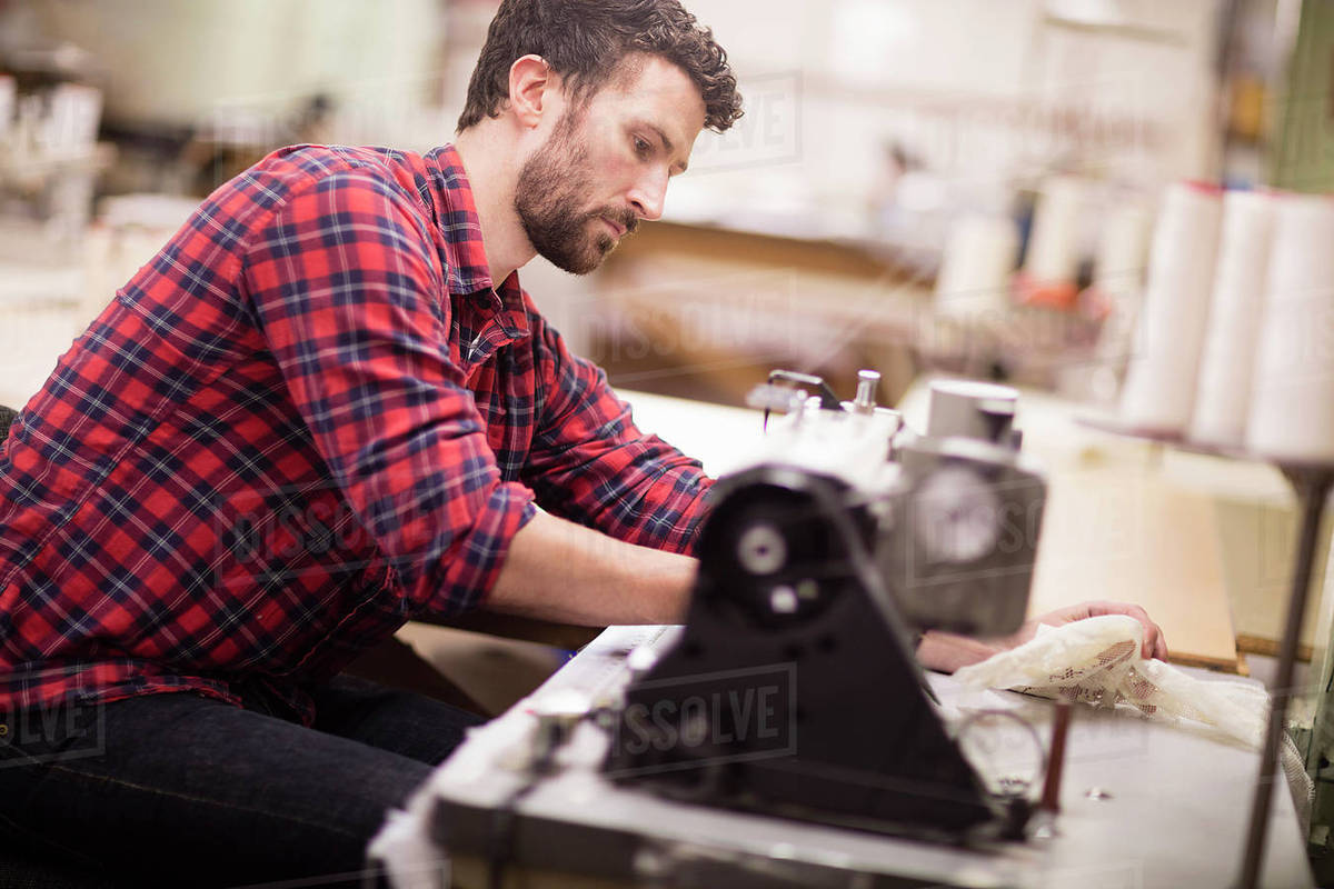 Male weaver using sewing machine in old textile mill - Royalty-free ...
