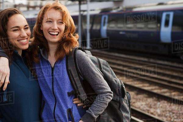 Young women smiling at train station - Stock Photo - Dissolve