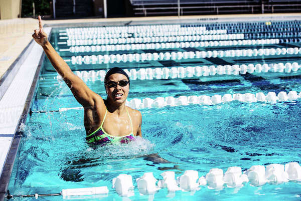 Swimmer in water in pool gesturing triumph - Stock Photo - Dissolve
