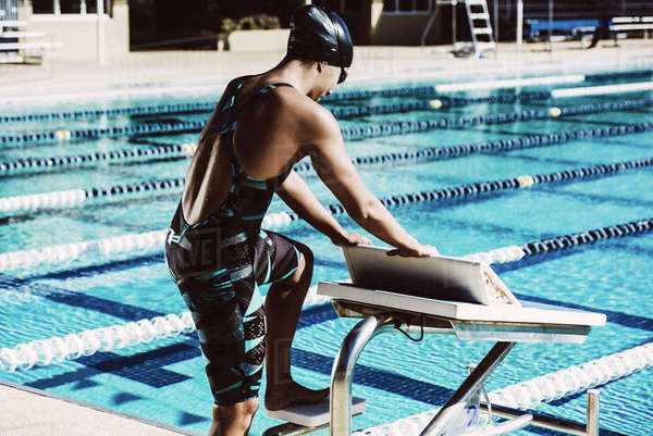 Swimmer getting onto pool diving board - Stock Photo - Dissolve