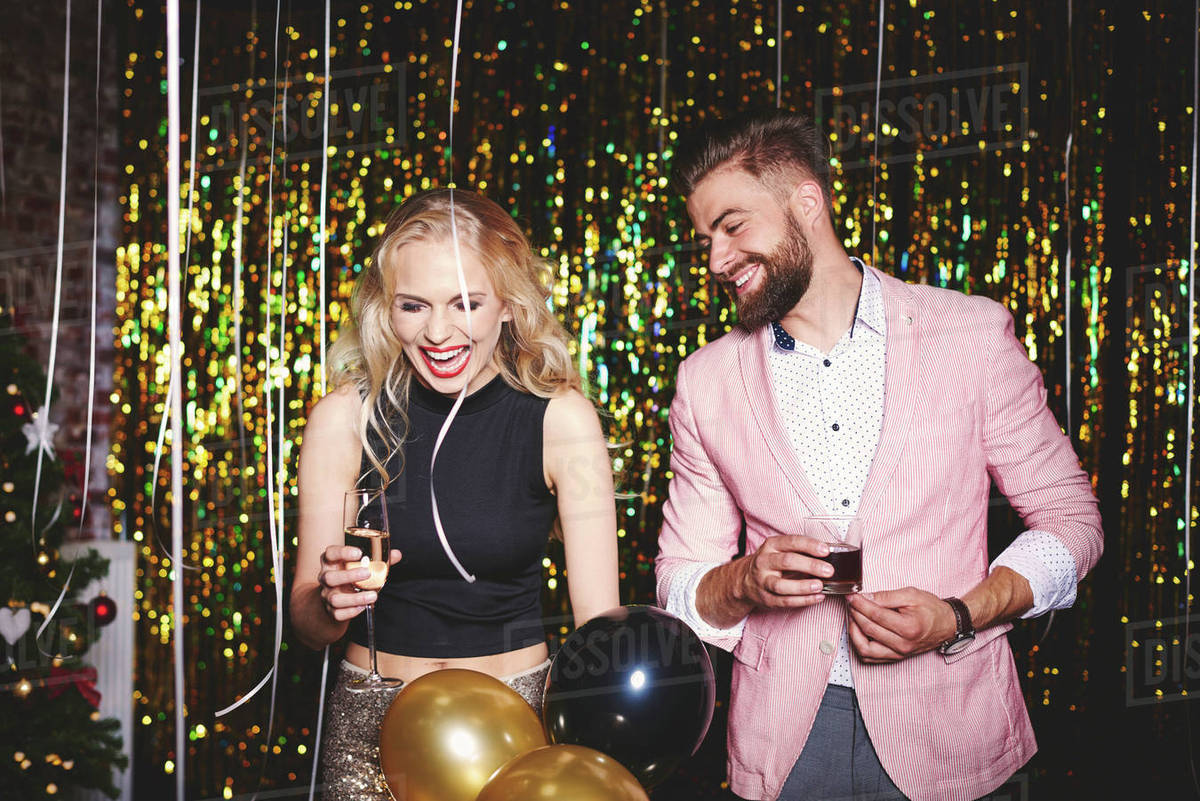 Man and woman at party, holding drinks, laughing - Stock Photo - Dissolve