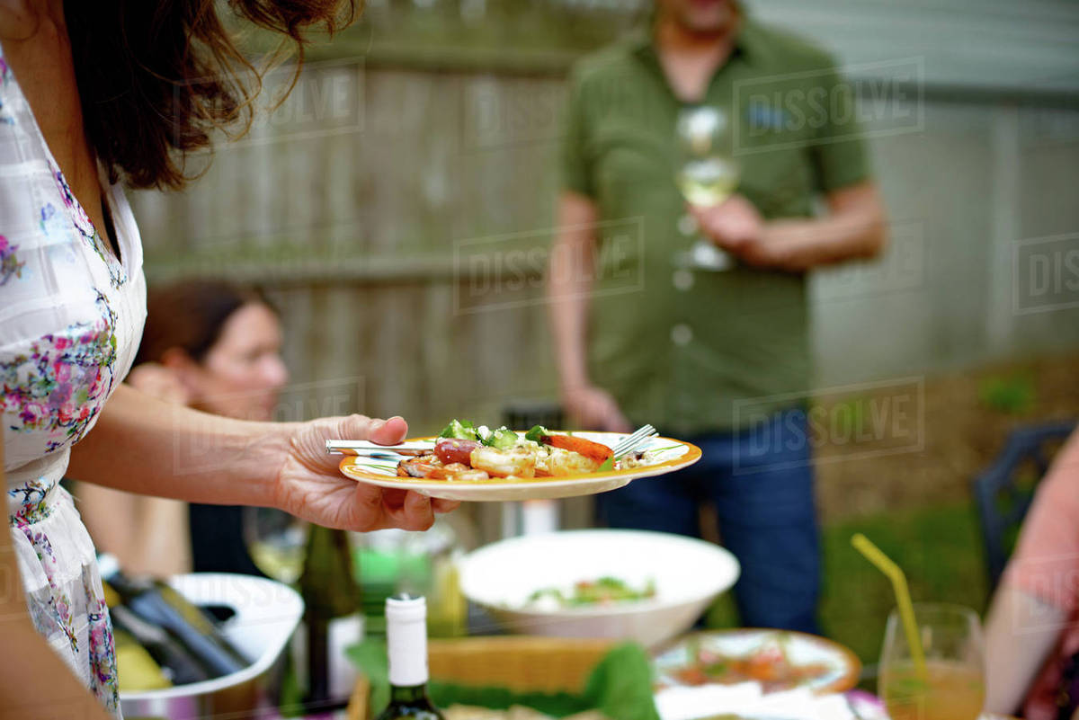 Woman at garden party holding plate of food, mid section - Stock Photo ...
