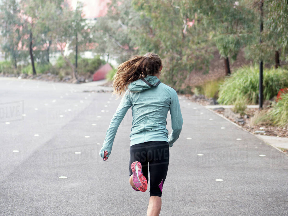 Rear view of female runner running by park - Royalty-free Stock Photo ...