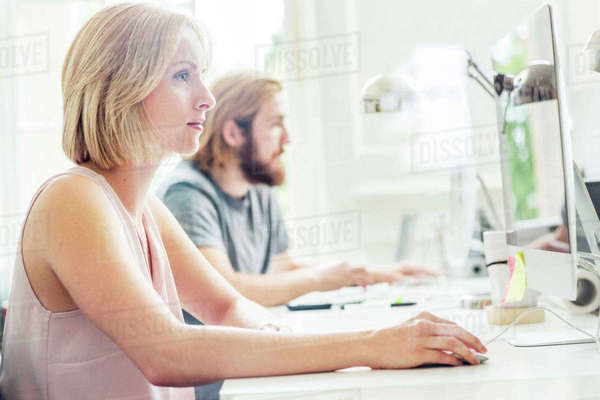 Male and female designers using desktop computers in creative studio ...