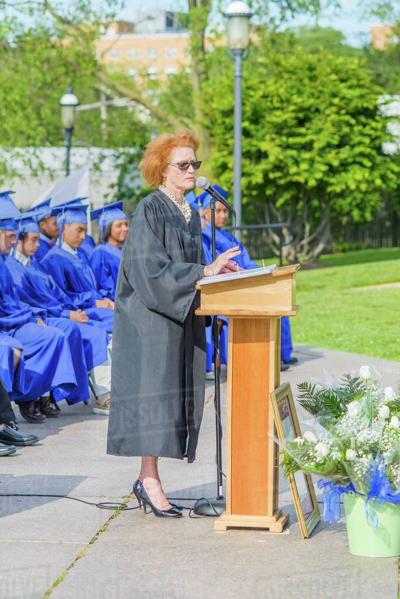 Principle standing at podium, giving speech, on graduation day ...