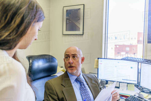 Over shoulder view of manager having discussion with office worker at ...