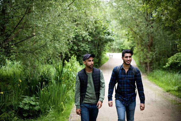 Friends walking on pathway in park - Royalty-free Stock Photo | Dissolve