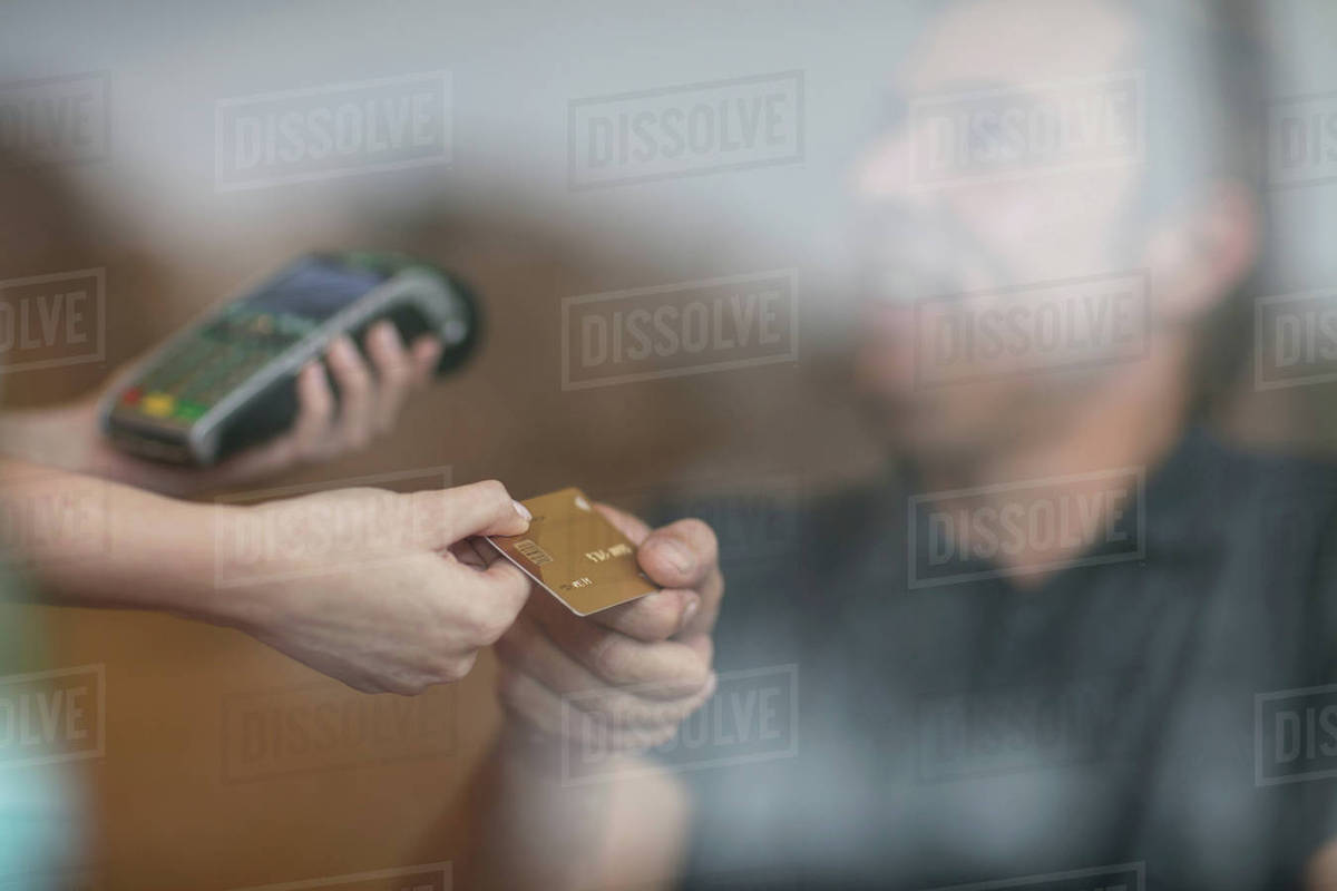 Customer handing credit card to waitress for payment on card machine ...