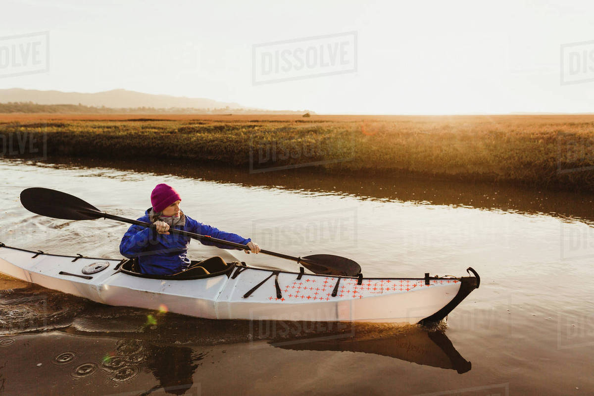 Mid adult woman kayaking on river at sunset, Morro Bay, California, USA ...