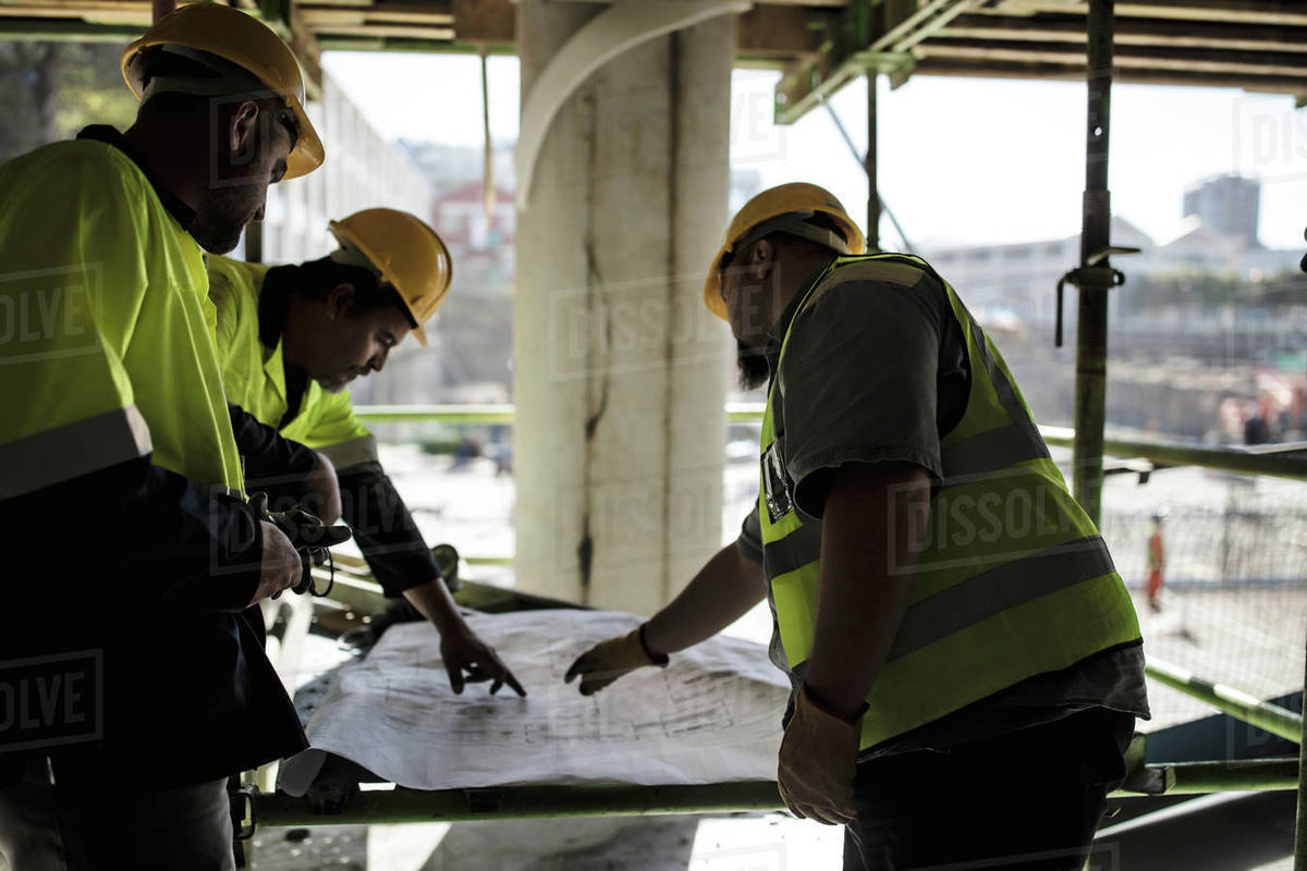Construction workers looking at plans - Stock Photo - Dissolve