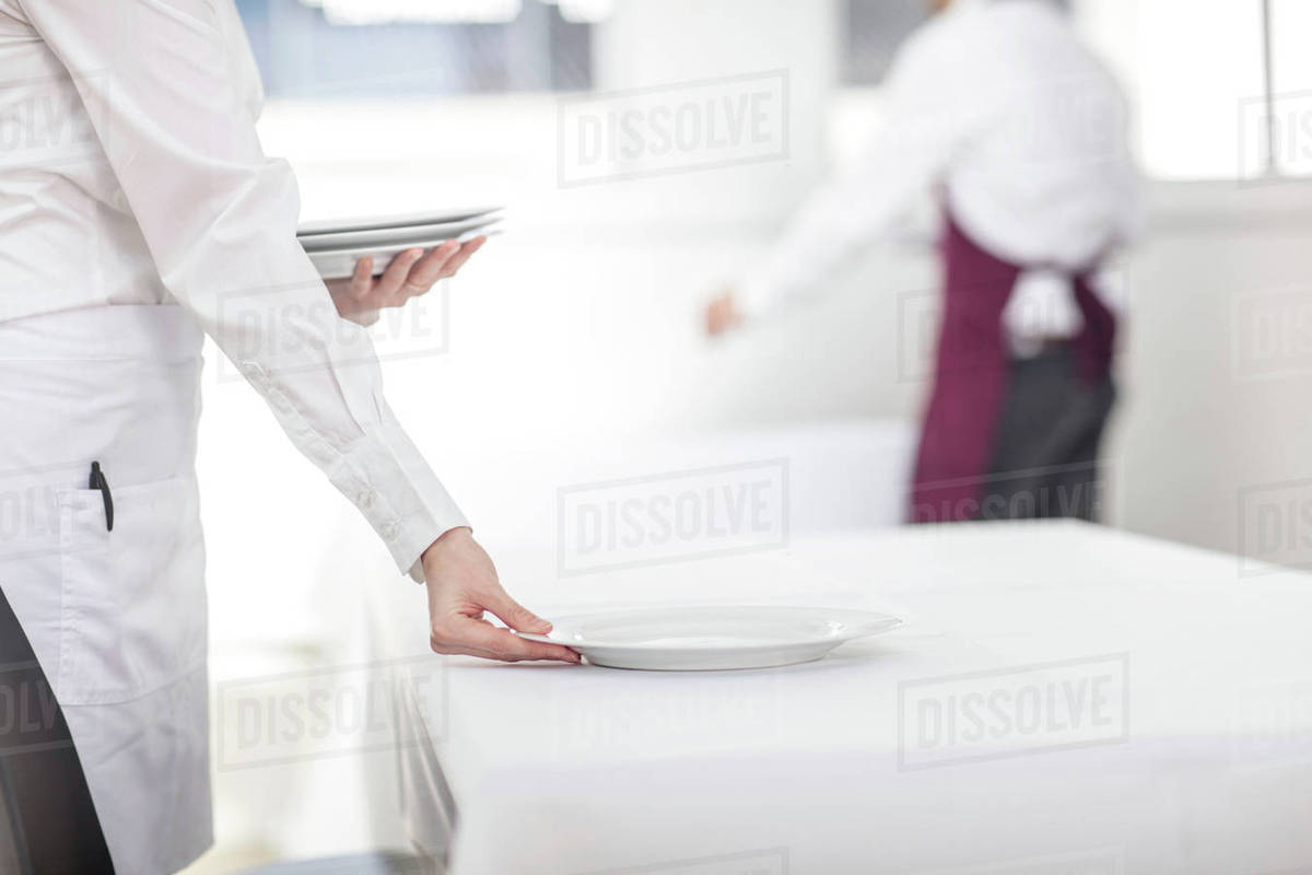 Waitress laying table in restaurant, mid section - Royalty-free Stock ...