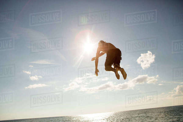 Young man jumping into water, mid air, rear view - Royalty-free Stock ...