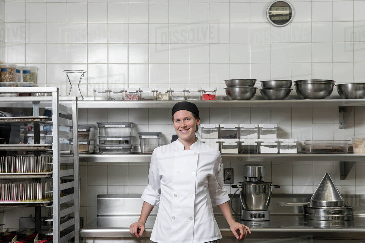 Portrait of chef in commercial kitchen looking at camera smiling ...