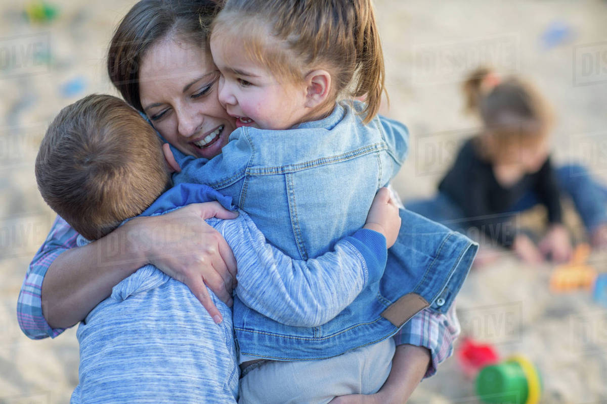 Mid adult woman hugging two young children - Royalty-free Stock Photo ...