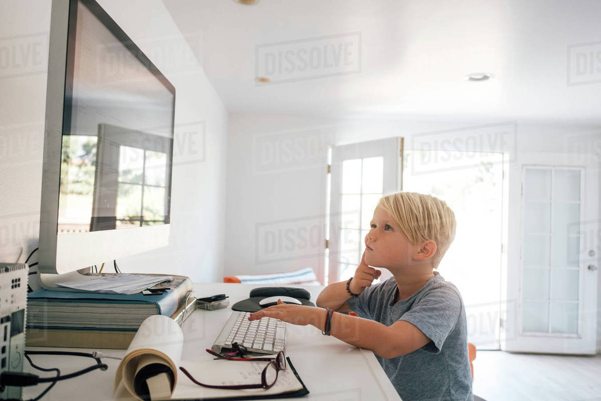 Confused boy looking at computer screen - Stock Photo - Dissolve