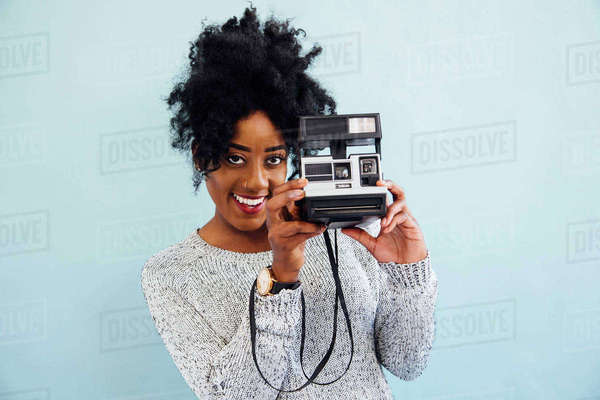 Woman with instant camera looking at camera smiling - Royalty-free ...