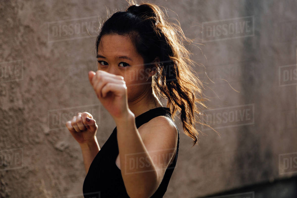 Portrait of young woman exercising outdoors, in fighting stance - Stock ...