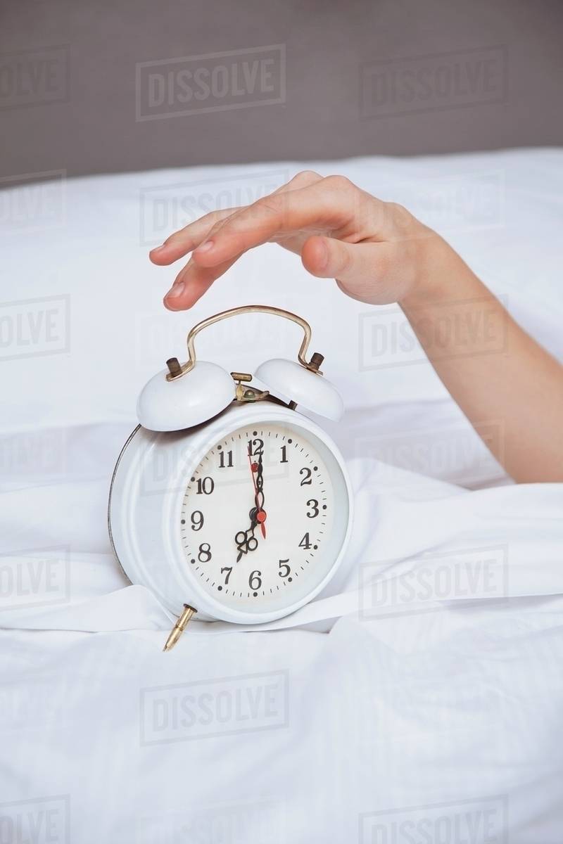 Female hand reaching for alarm clock - Royalty-free Stock Photo | Dissolve