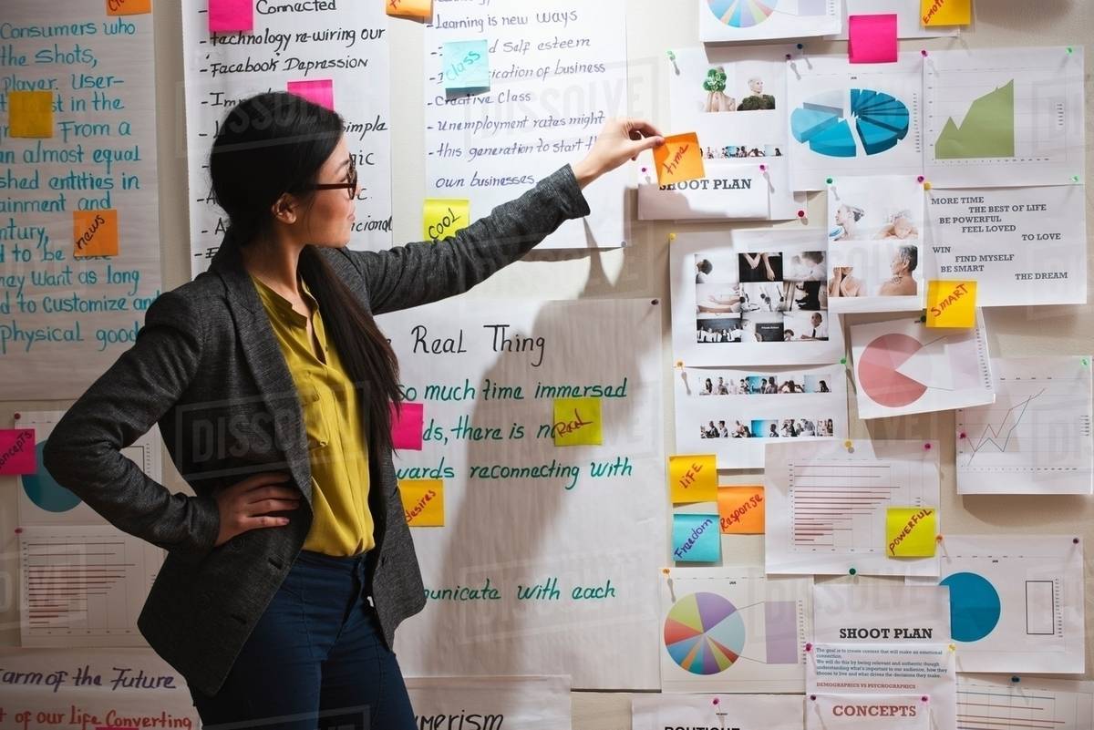 Woman with adhesive notes and papers on wall - Stock Photo - Dissolve
