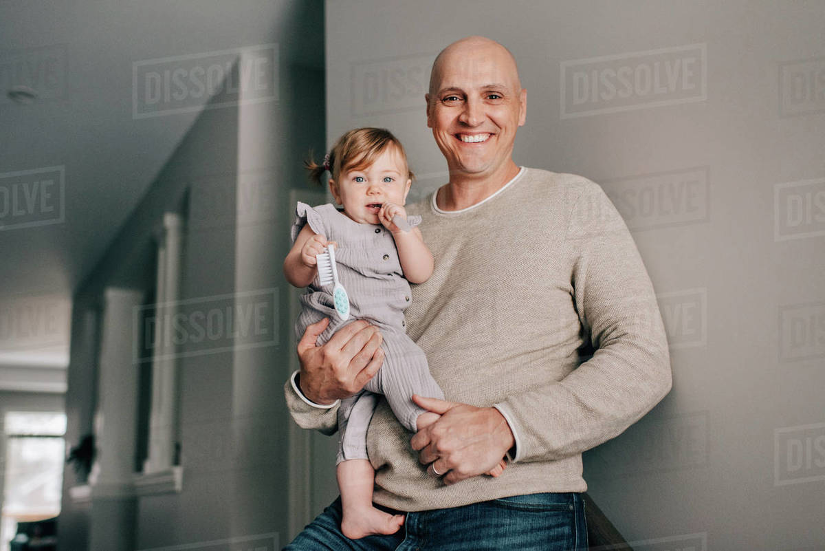 Father carrying baby daughter in hallway, portrait - Royalty-free Stock ...