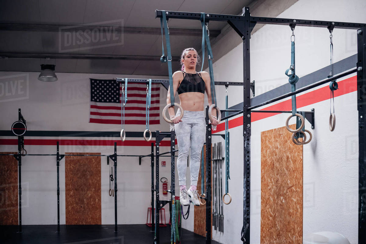 Young woman balancing on gymnastic rings in gym - Royalty-free Stock ...