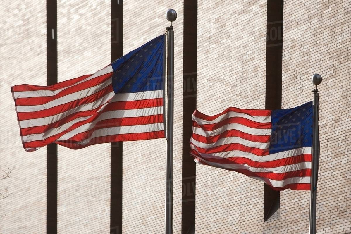 American flags flying by skyscraper - Royalty-free Stock Photo | Dissolve