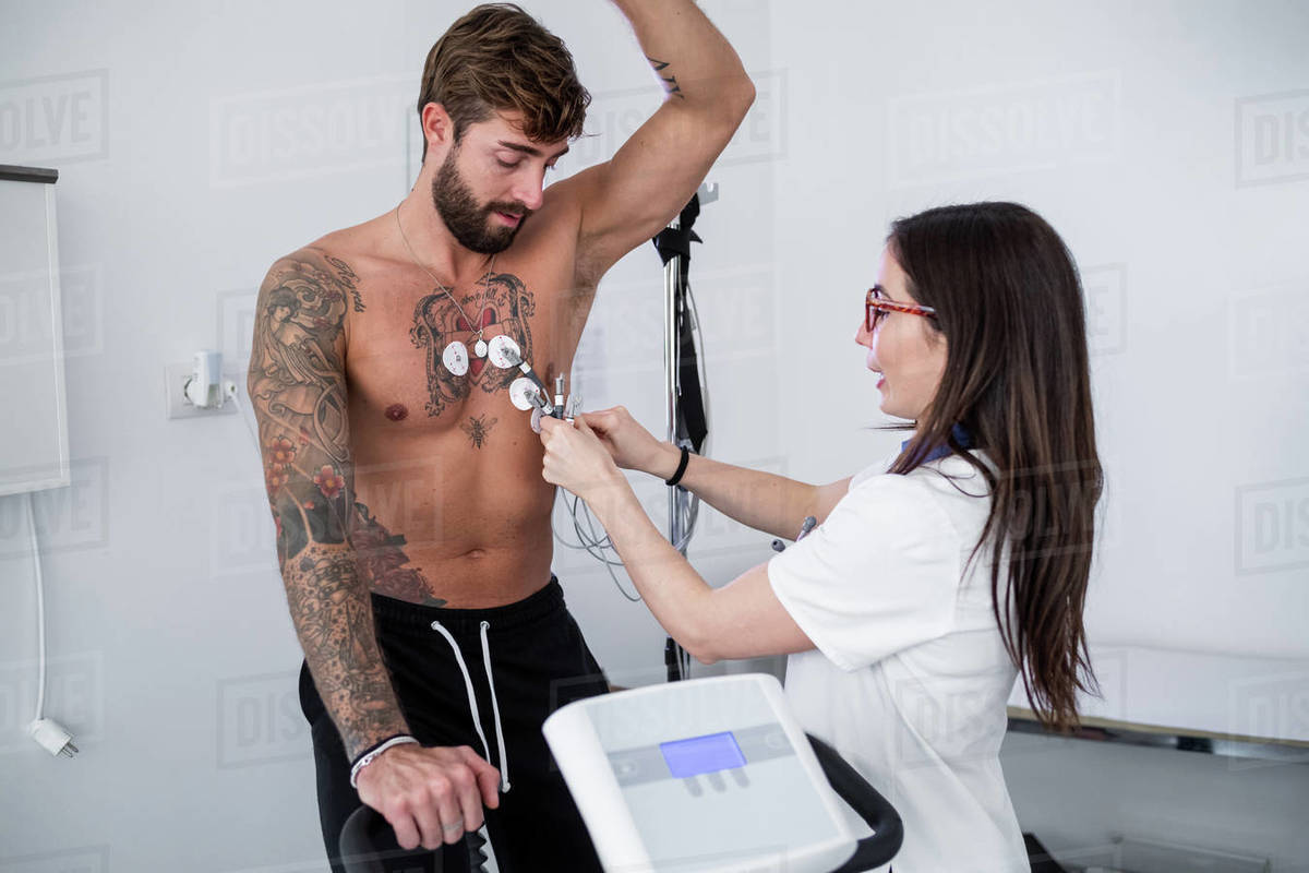 Nurse performing ECG test on patient in consultation room - Royalty ...