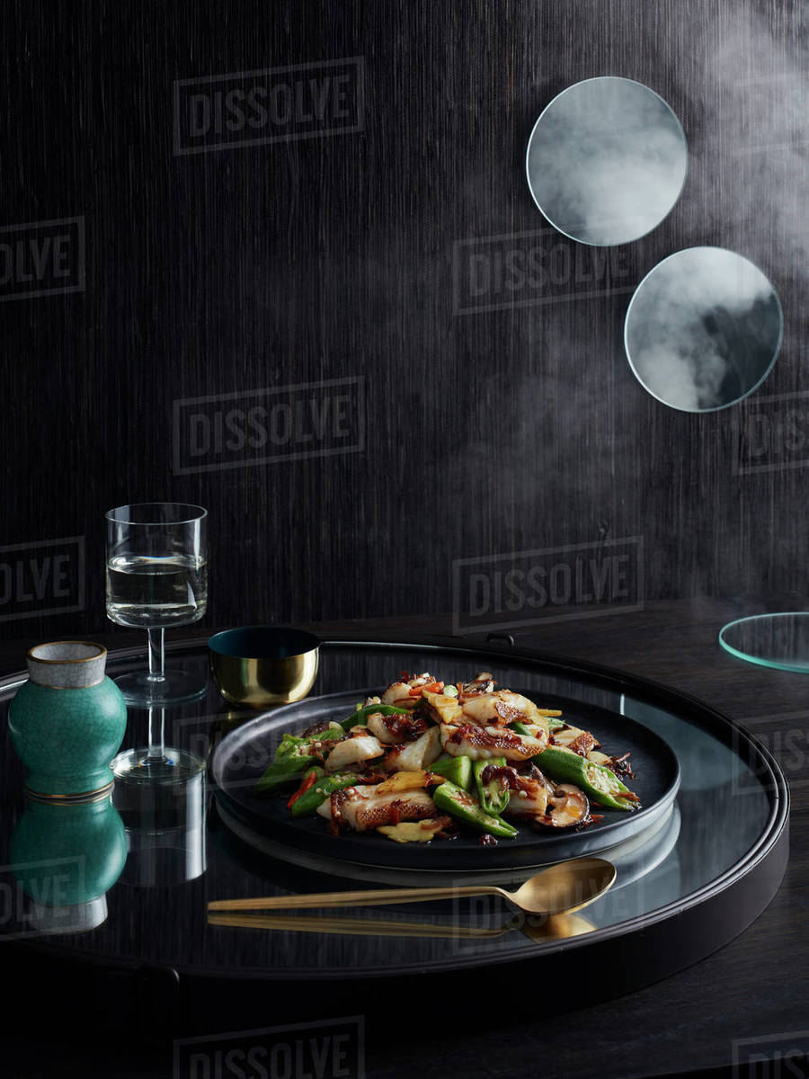 Rustic low key still life with plate of stir fry coral trout, okra and ...