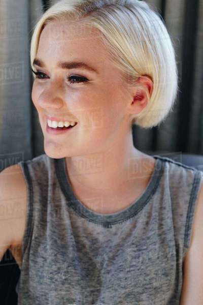 Happy young woman with blond bobbed hair looking away, head and ...