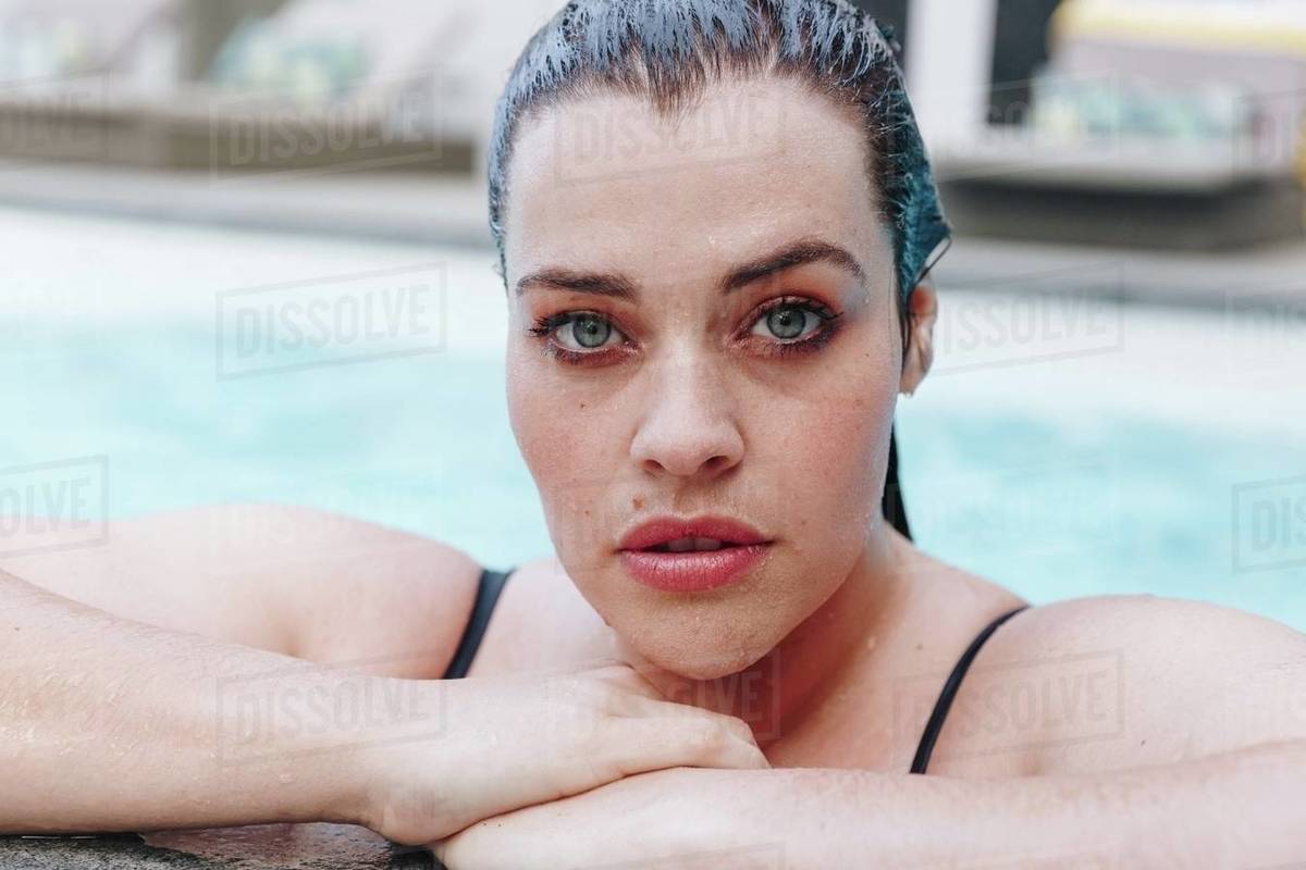Sultry mid adult woman in outdoor swimming pool, head and shoulder ...