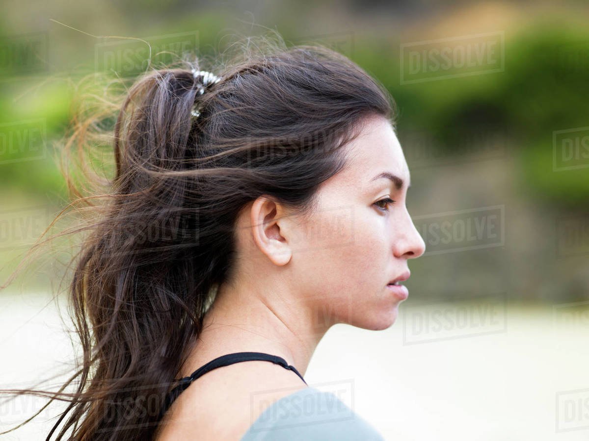 Young female surfer gazing from beach, head and shoulder side view ...