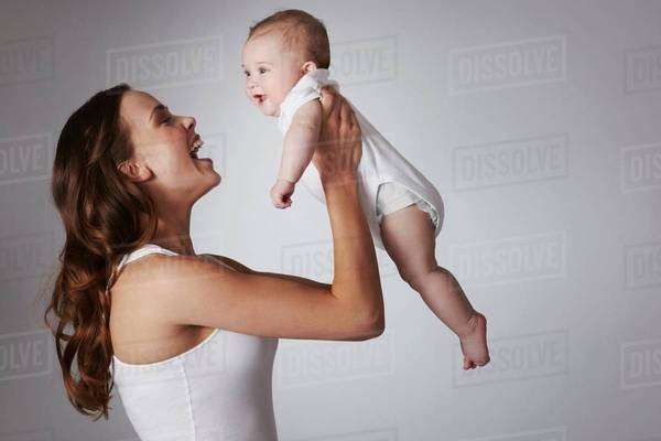Mother lifting baby daughter - Stock Photo - Dissolve