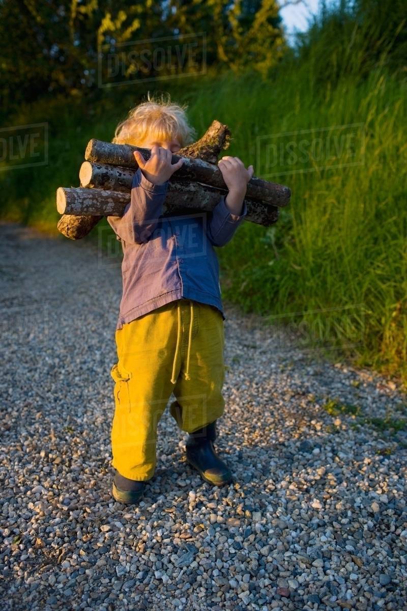 A boy carrying logs - Royalty-free Stock Photo | Dissolve