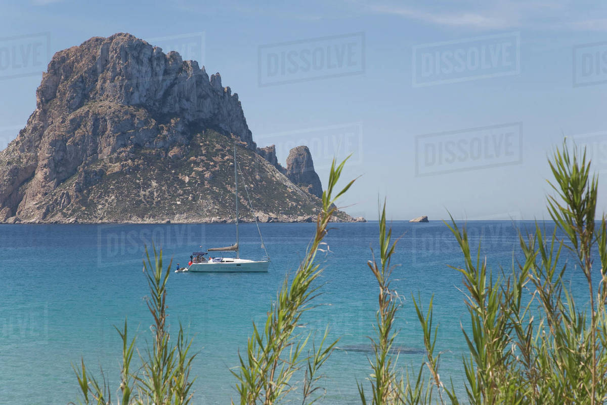 Boat floating in ocean by rock formation - Stock Photo - Dissolve