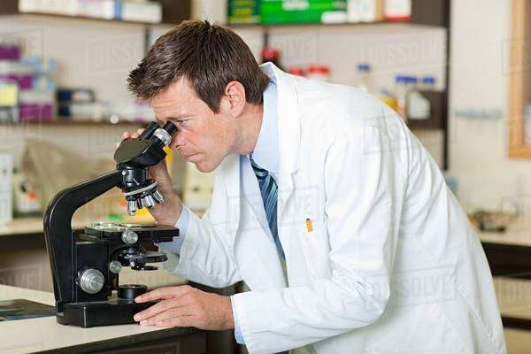 Doctor using microscope - Royalty-free Stock Photo | Dissolve