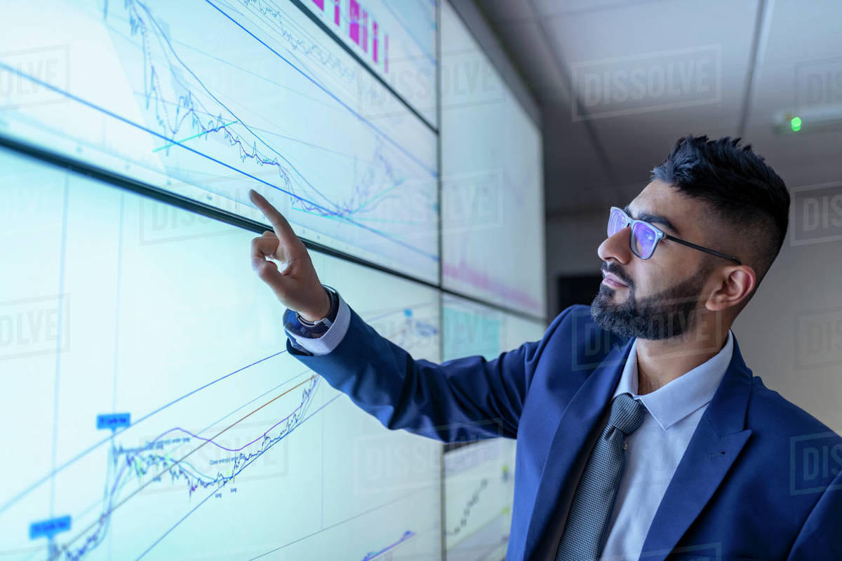 Businessman pointing to charts on interactive screens - Royalty-free ...