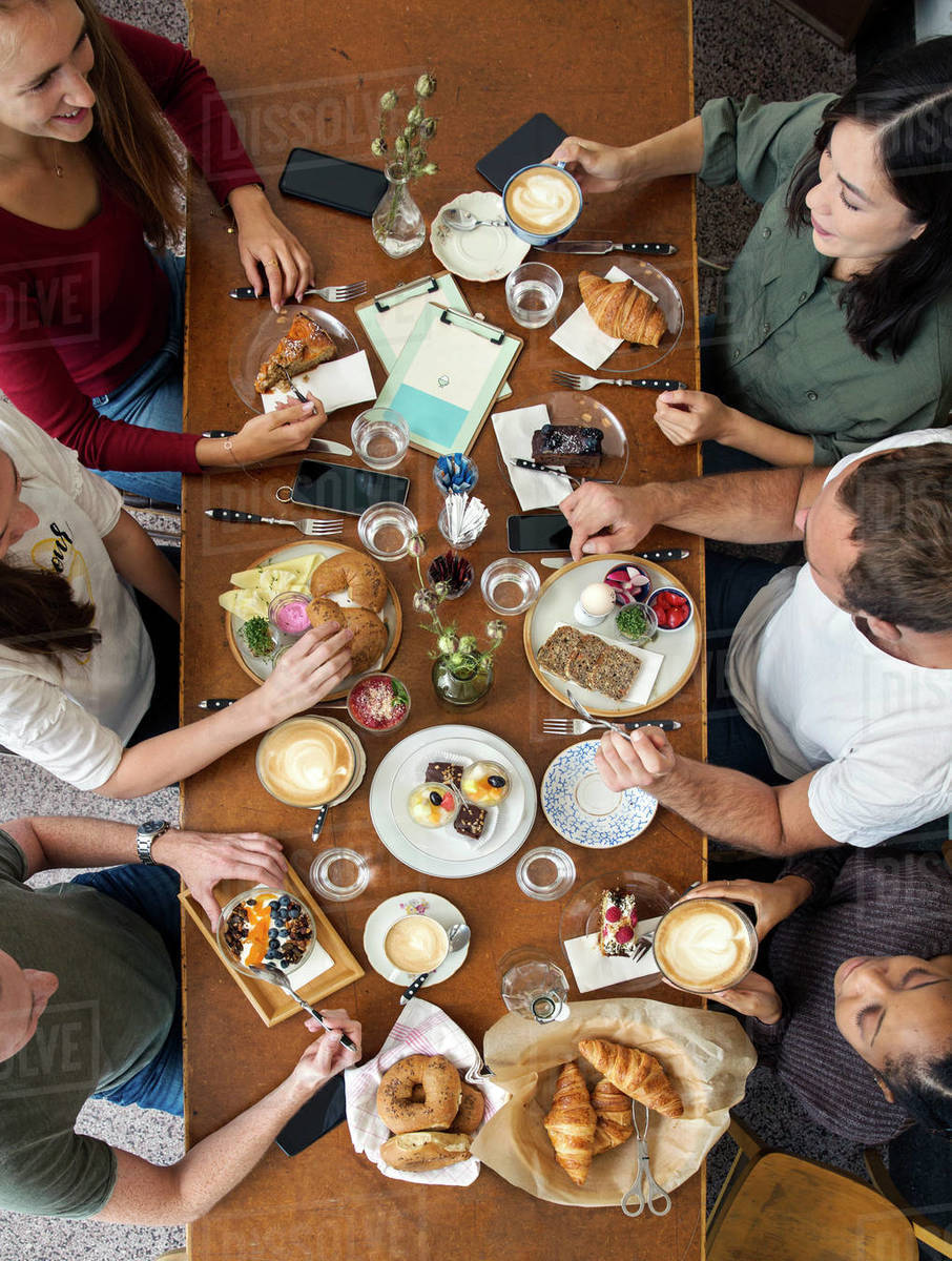 Overhead view of group of friends enjoying breakfast at restaurant ...