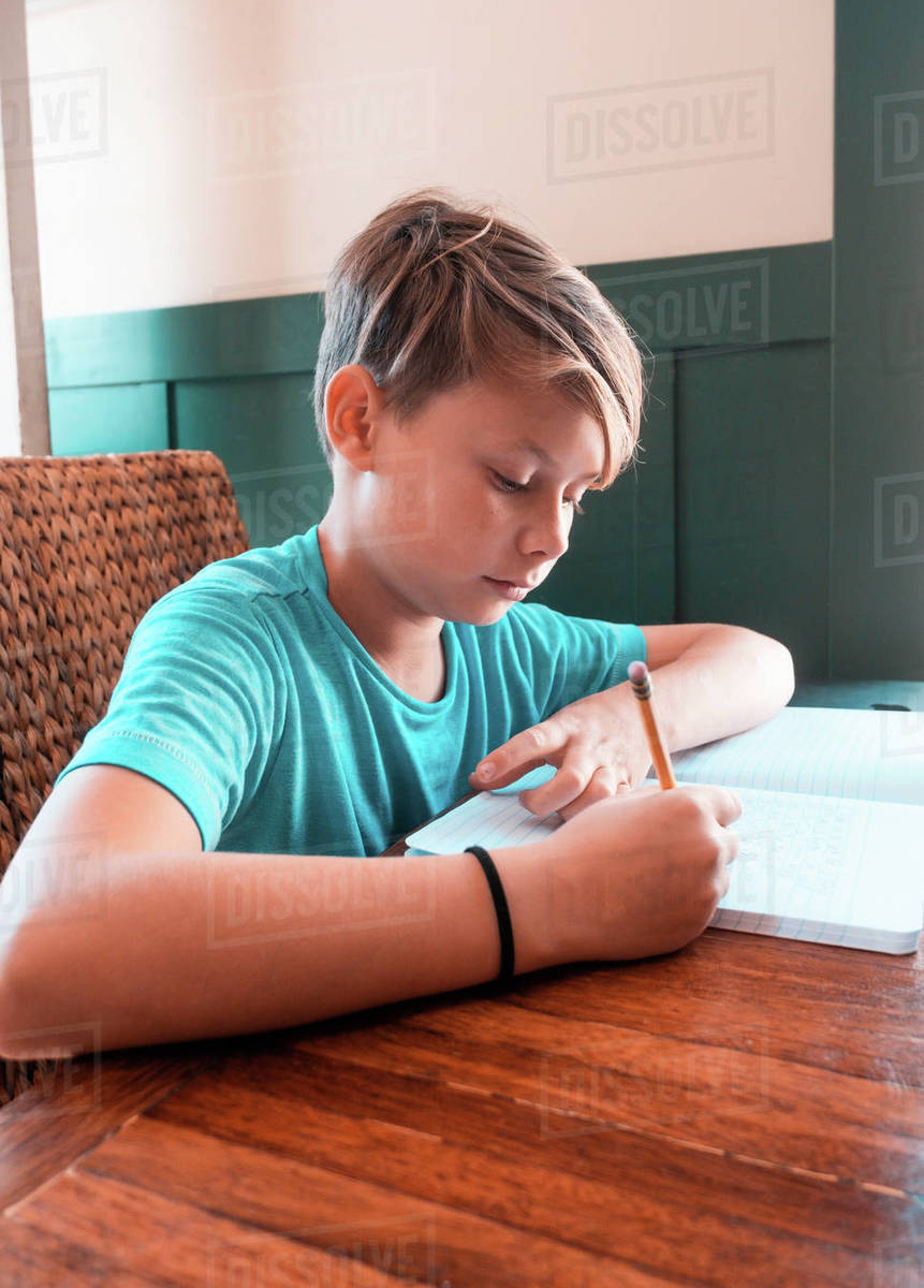 Boy doing homework at table - Stock Photo - Dissolve